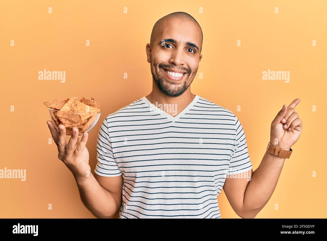 Hispanic adult man holding nachos potato chips smiling happy pointing ...