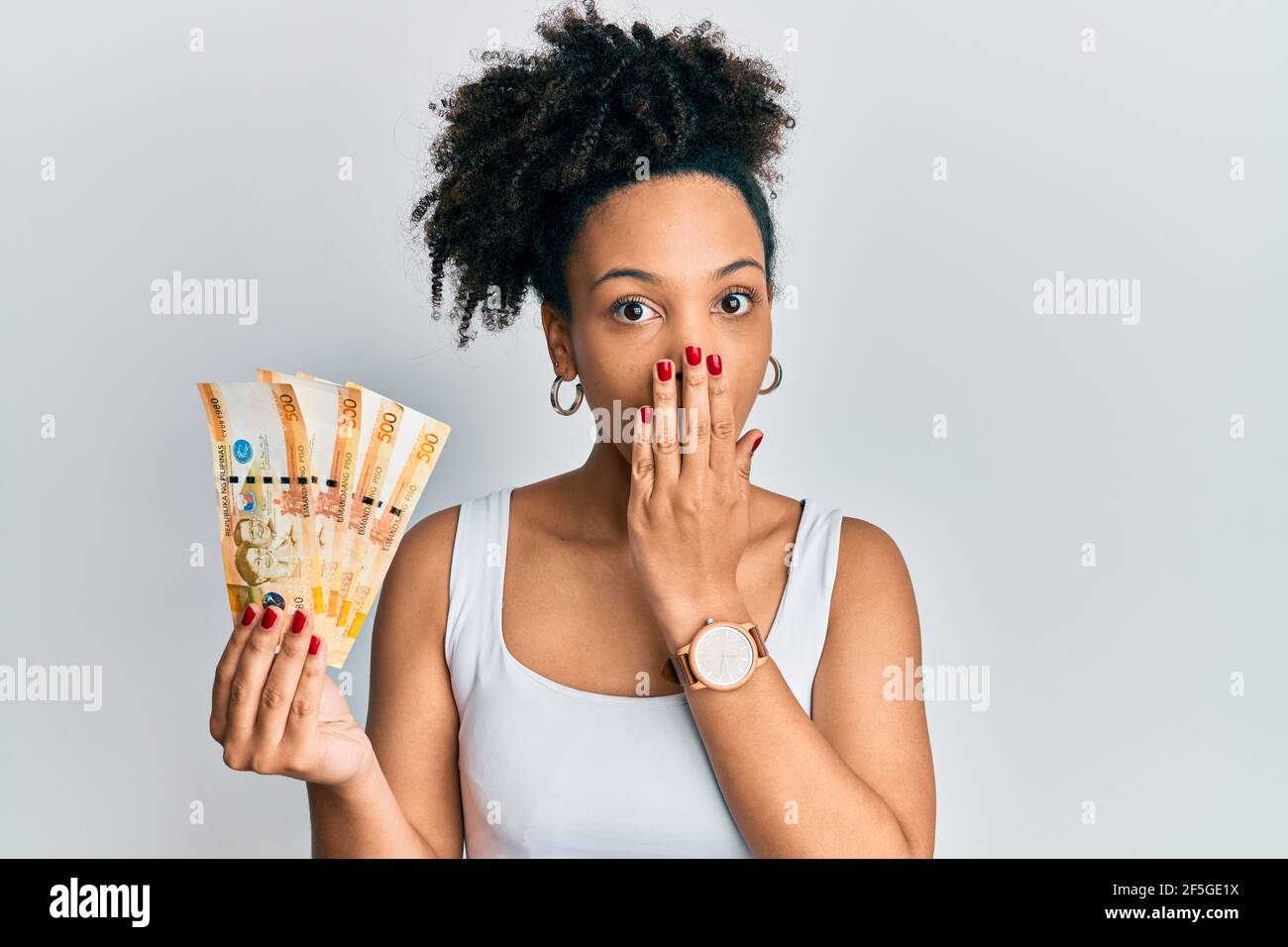 Young african american girl holding philippine peso banknotes covering ...