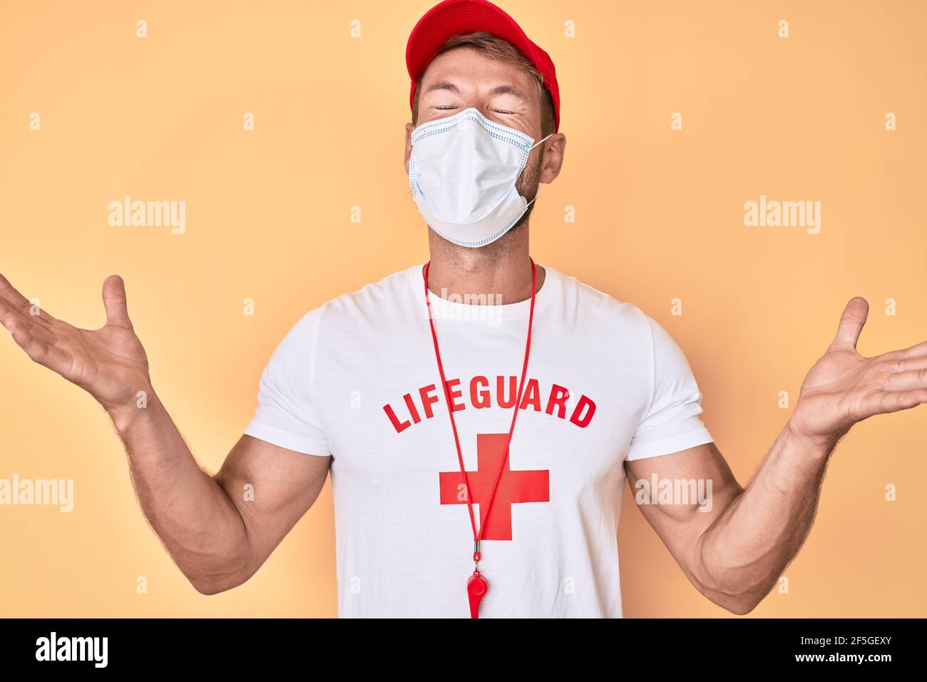 Young caucasian man wearing lifeguard t shirt using medical mask ...