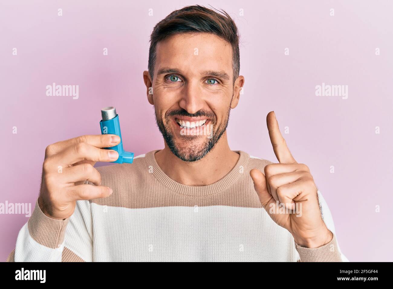 Handsome man with beard holding medical asthma inhaler smiling with an ...