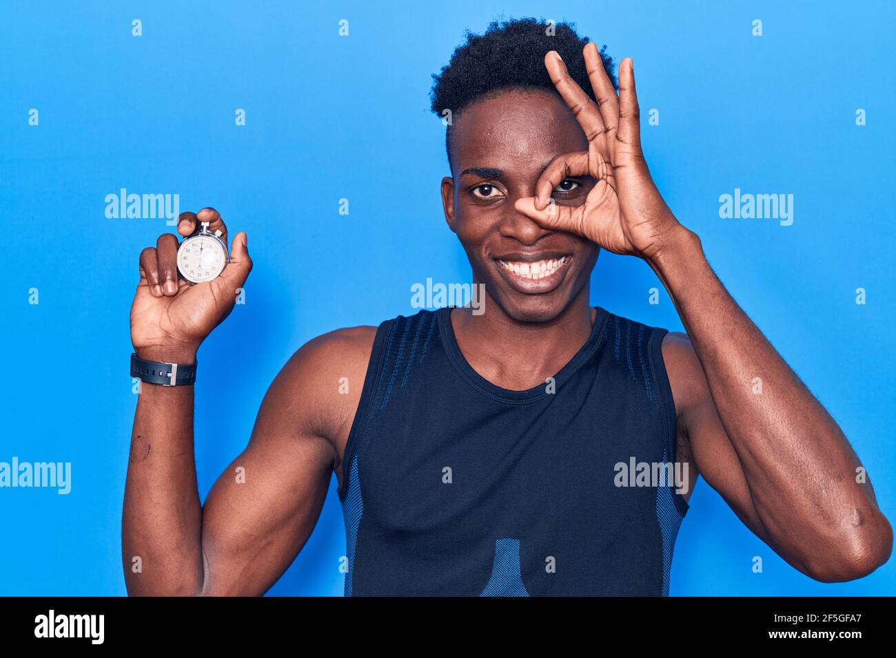 Young african american man holding stopwatch smiling happy doing ok ...