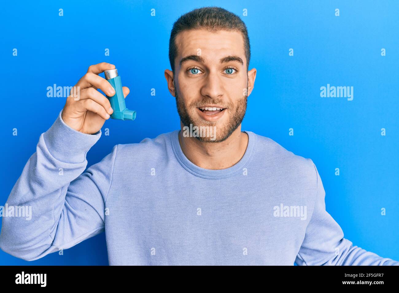 Young caucasian man holding medical asthma inhaler celebrating ...