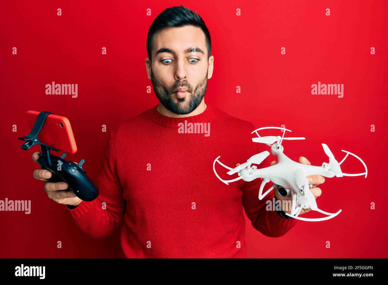 Young hispanic man holding drone and remote control with smartphone ...