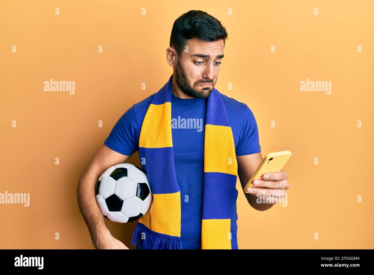Young hispanic man football hooligan holding soccer ball using ...