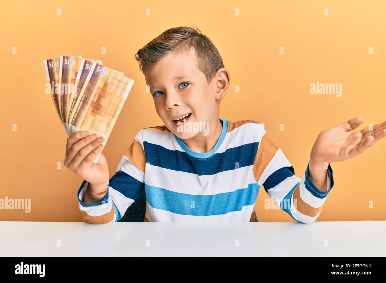 Adorable caucasian kid holding 500 norwegian krone banknotes sitting on ...