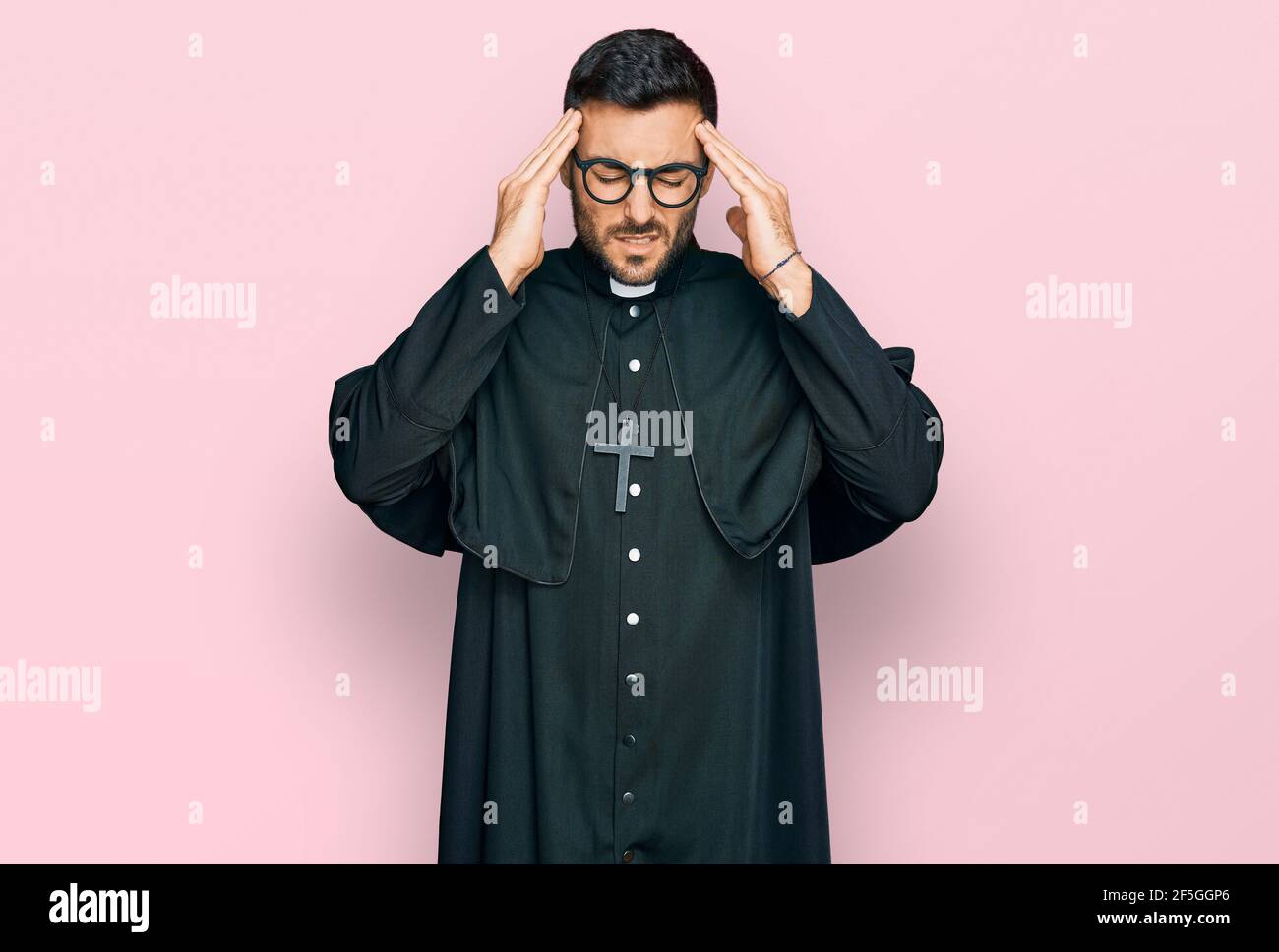 Young hispanic man wearing priest uniform suffering from headache ...