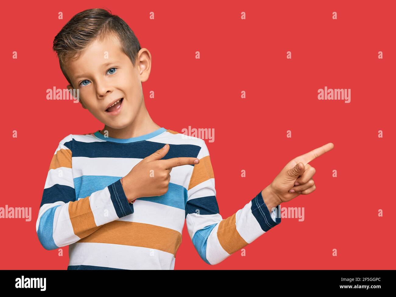 Adorable caucasian kid wearing casual clothes smiling and looking at ...
