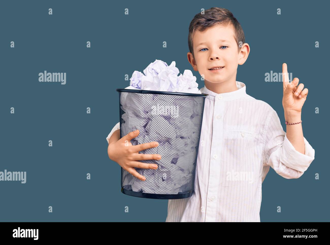 Cute blond kid holding paper bin full of crumpled papers surprised with ...