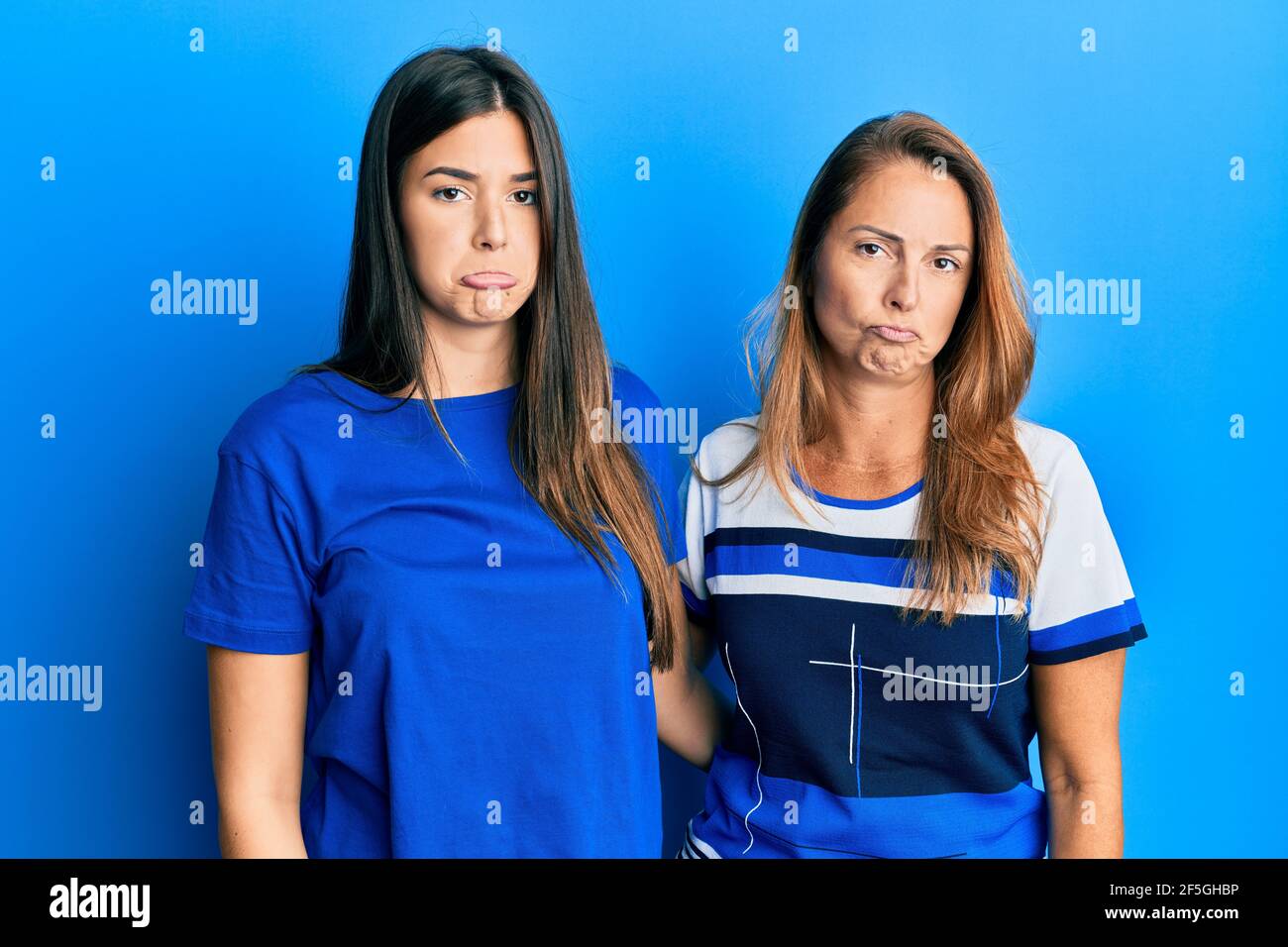 Hispanic family of mother and daughter wearing casual clothes over blue ...