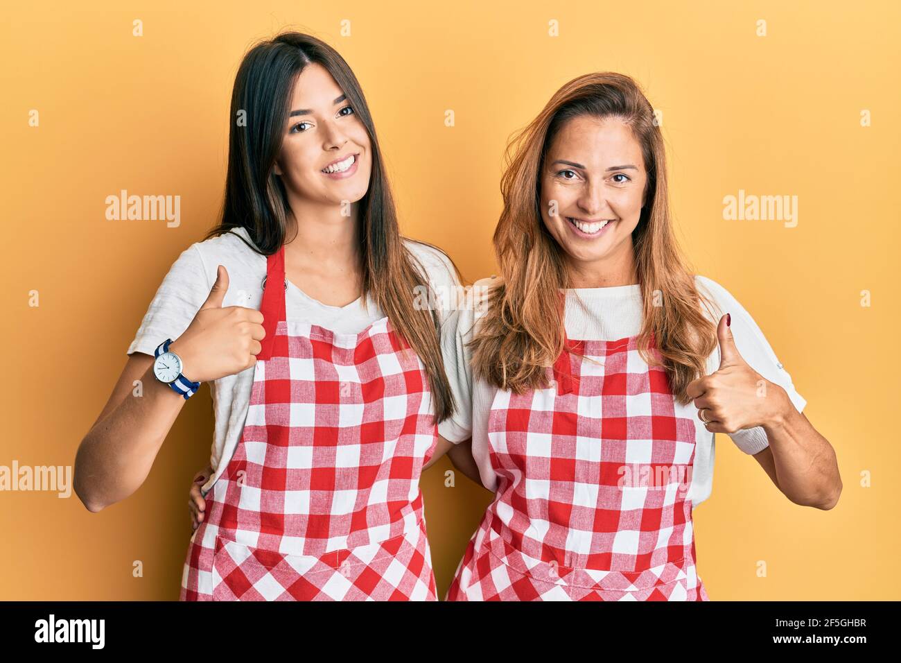 Hispanic family of mother and daughter wearing baker uniform over ...