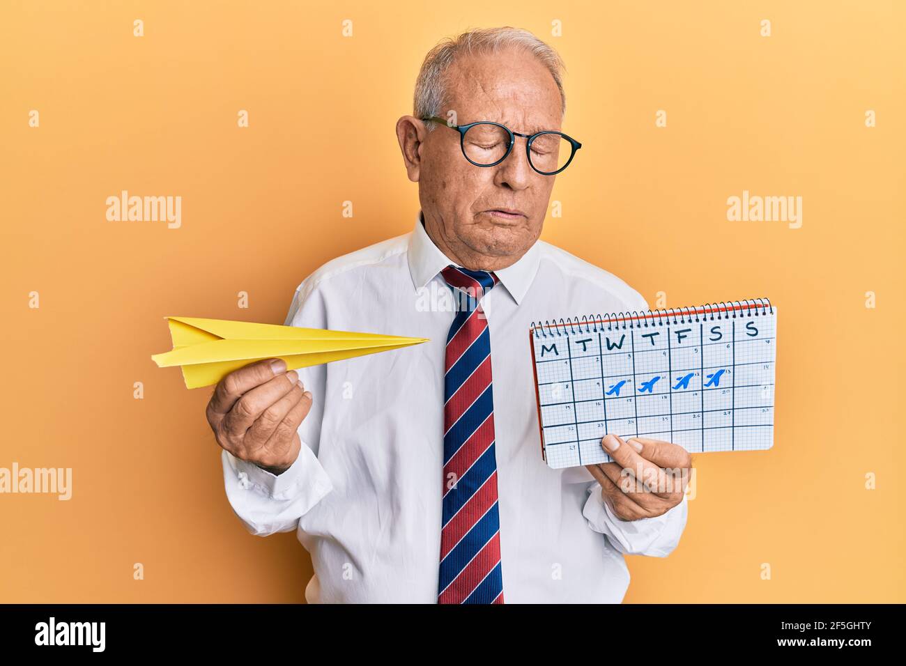 Senior caucasian man going on business trip holding paper airplane ...