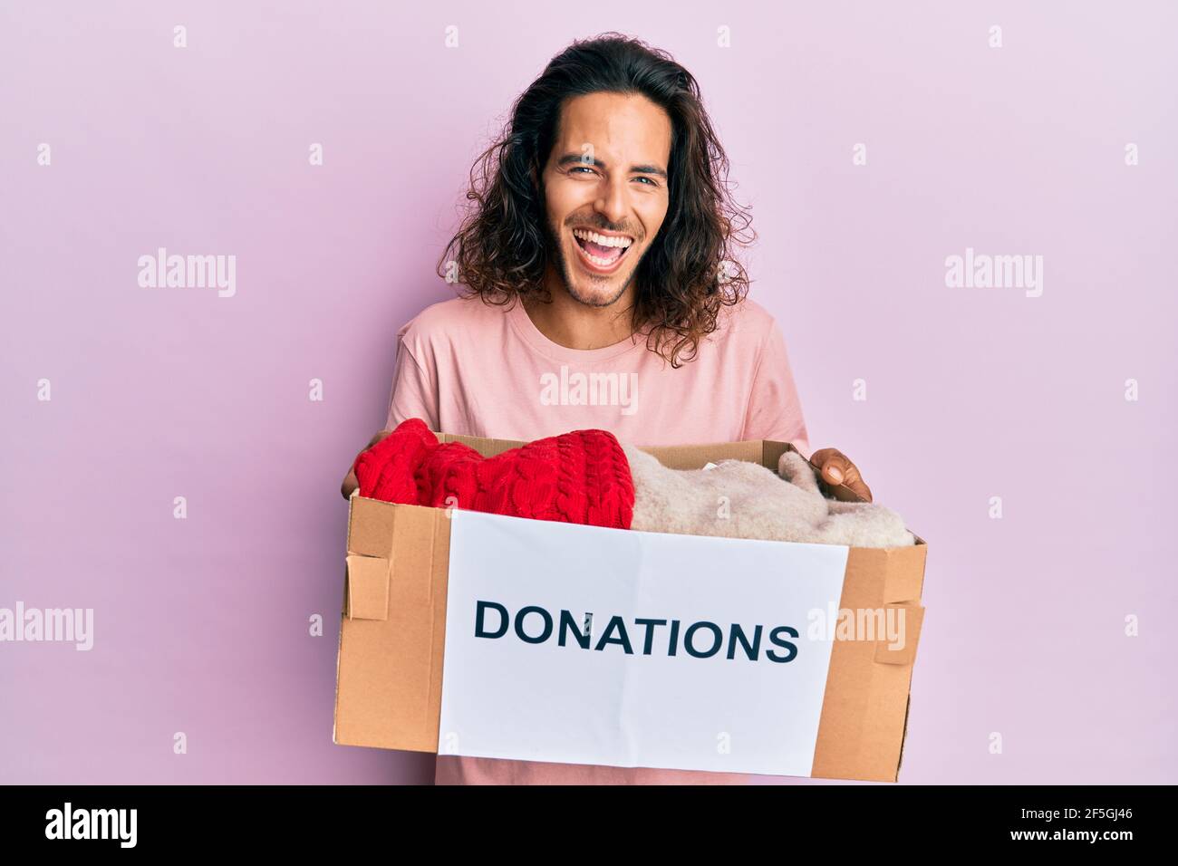 Young handsome man with long hair holding donations box for charity ...
