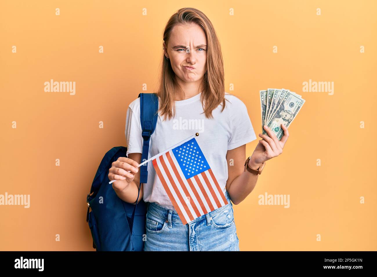 Beautiful blonde woman exchange student holding usa flag and dollars ...