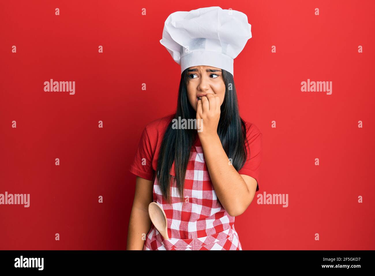 Young beautiful hispanic girl wearing baker uniform and cook hat ...