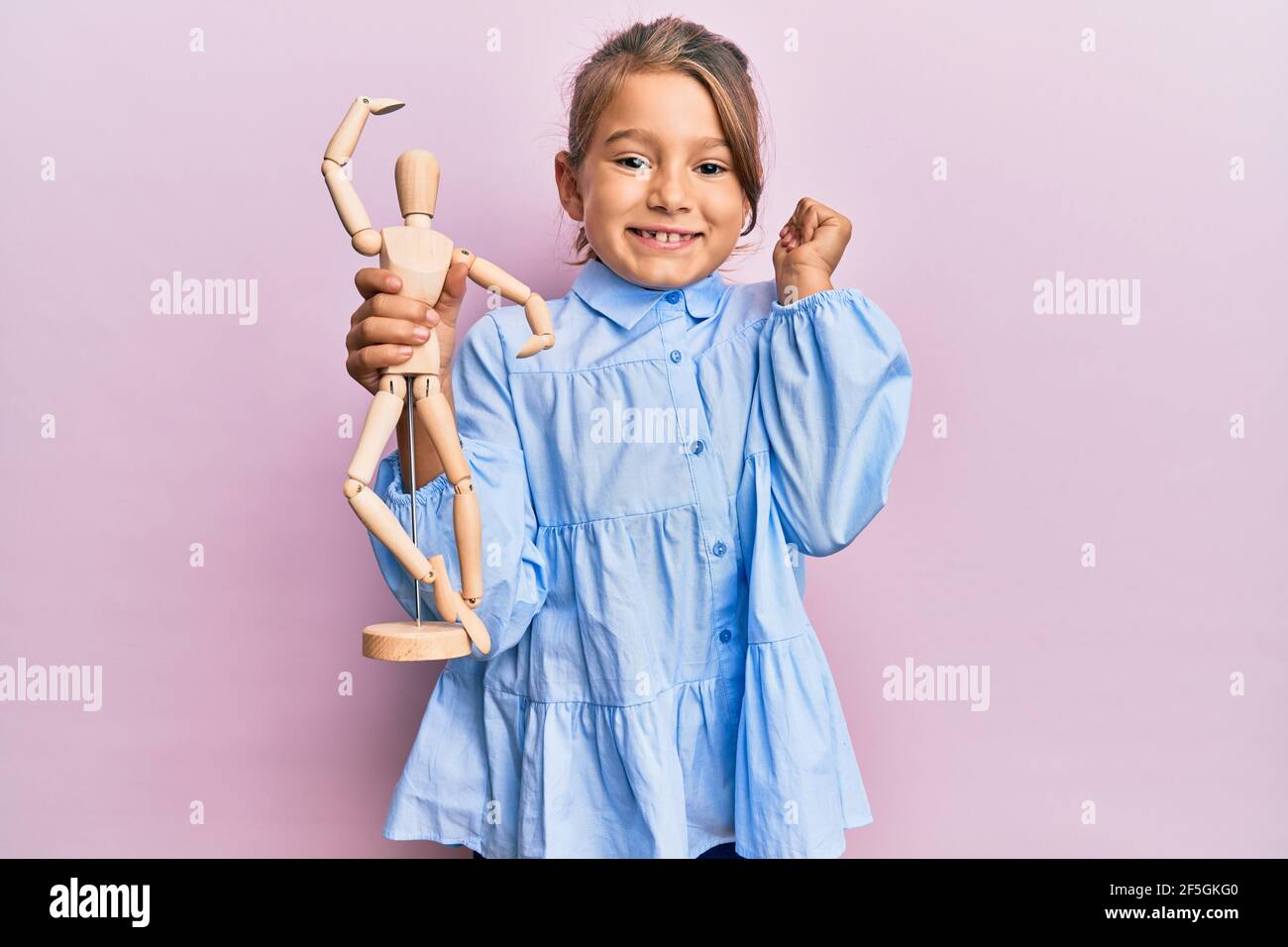 Little beautiful girl holding small wooden manikin screaming proud ...