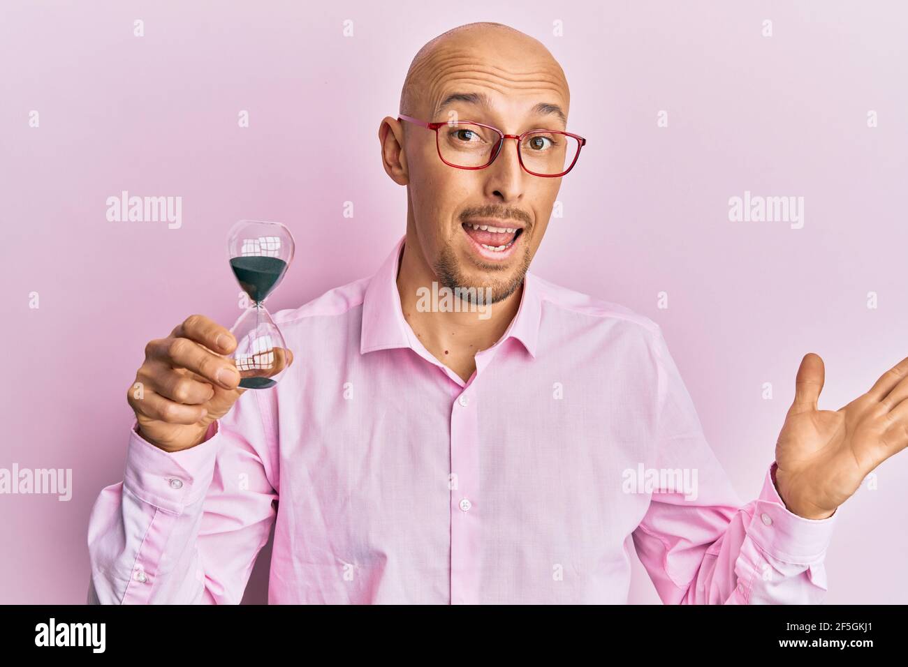 Bald man with beard holding sand clock celebrating victory with happy ...