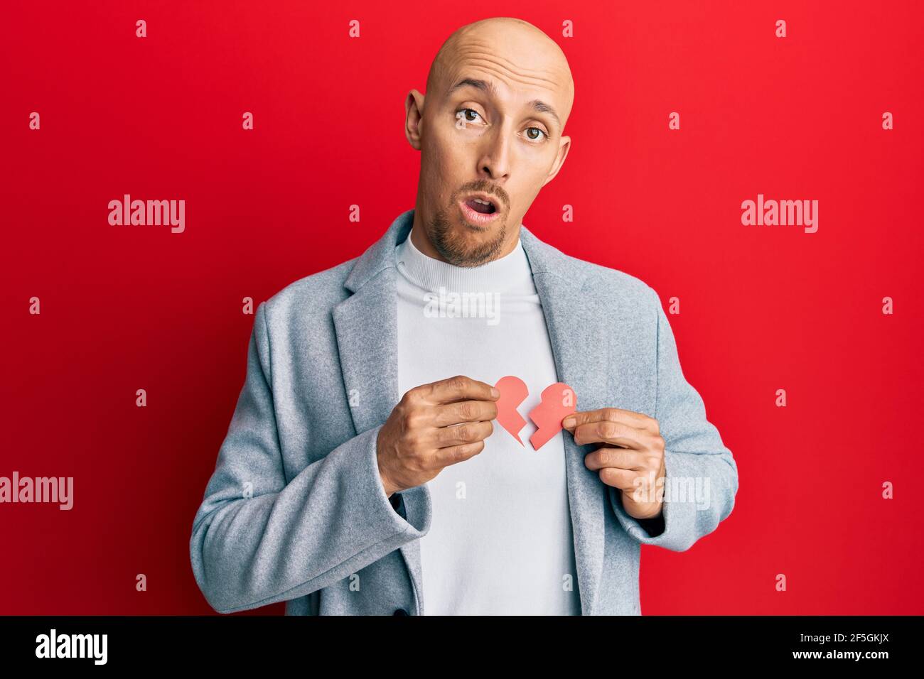 Bald man with beard holding broken heart paper shape in shock face ...