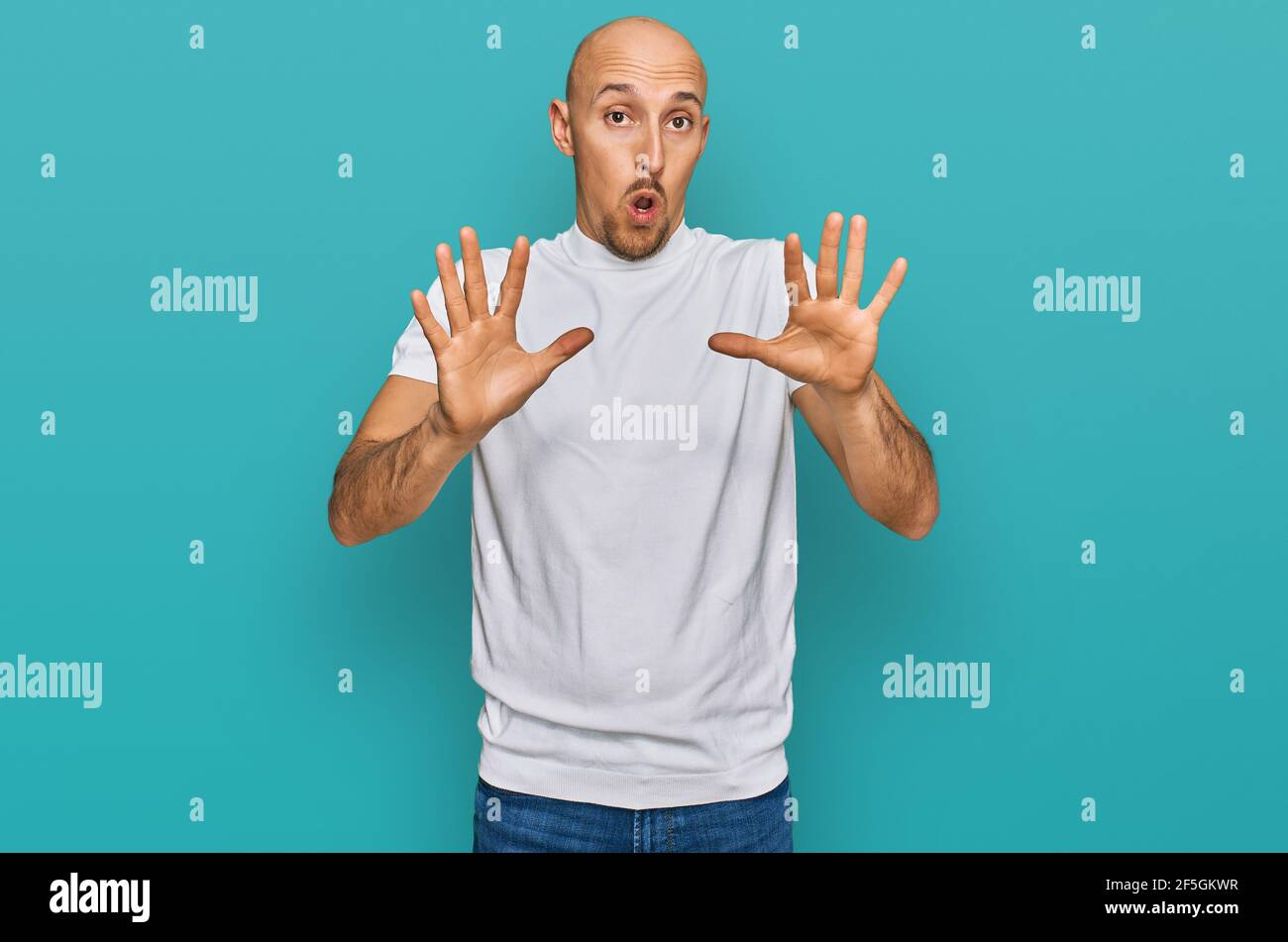 Bald man with beard wearing casual white t shirt afraid and terrified with fear expression stop ...
