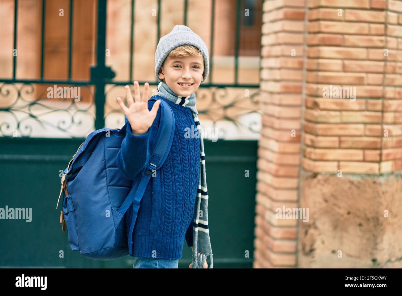 Adorable blond student kid saying goodbye with hand getting in the ...