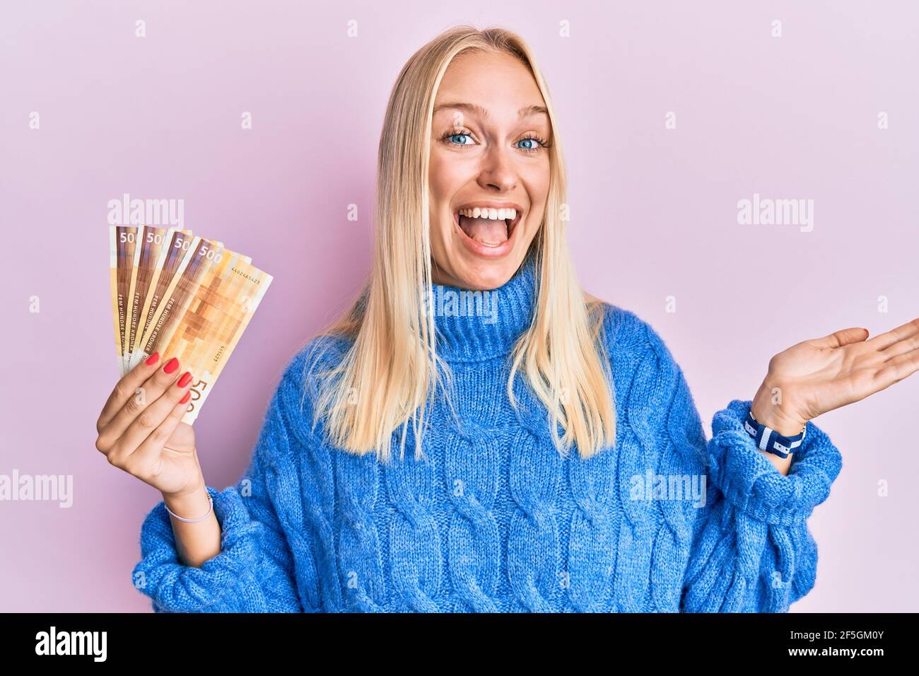 Young blonde girl holding 100 norwegian krone banknotes celebrating ...