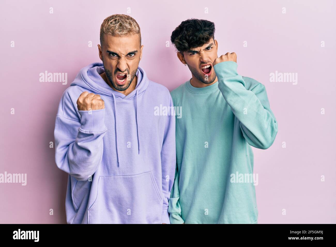 Homosexual gay couple standing together wearing casual clothes angry ...