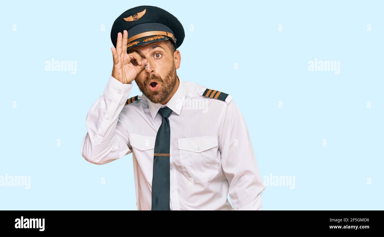 Handsome man with beard wearing airplane pilot uniform doing ok gesture ...