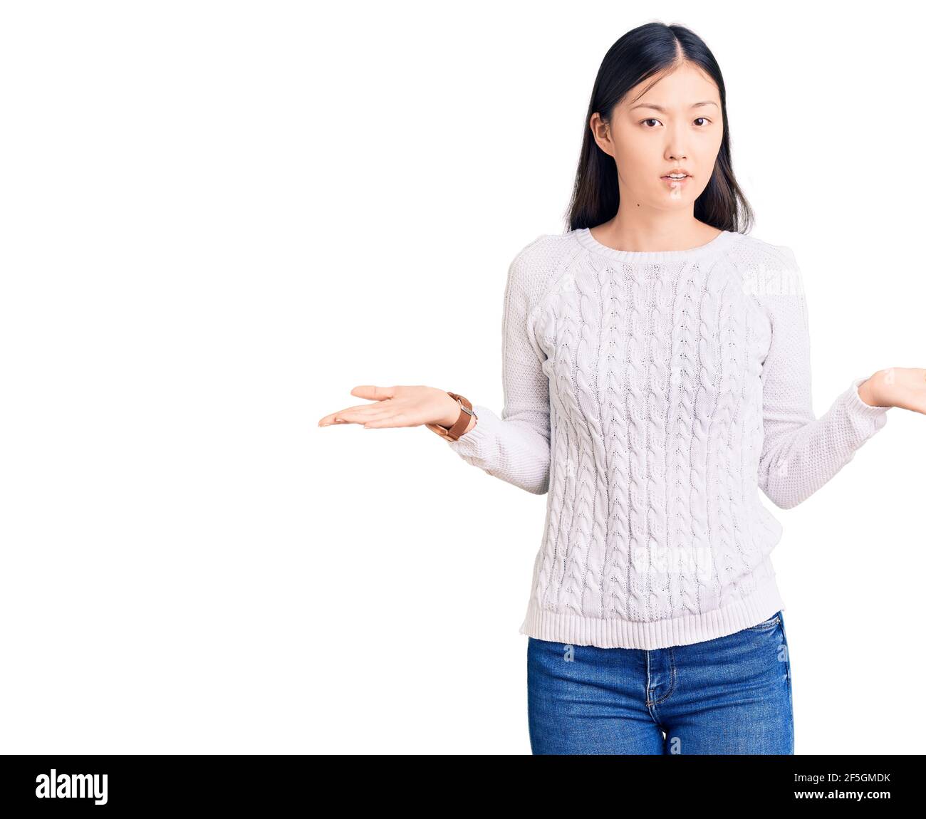 Young beautiful chinese woman wearing casual sweater clueless and ...