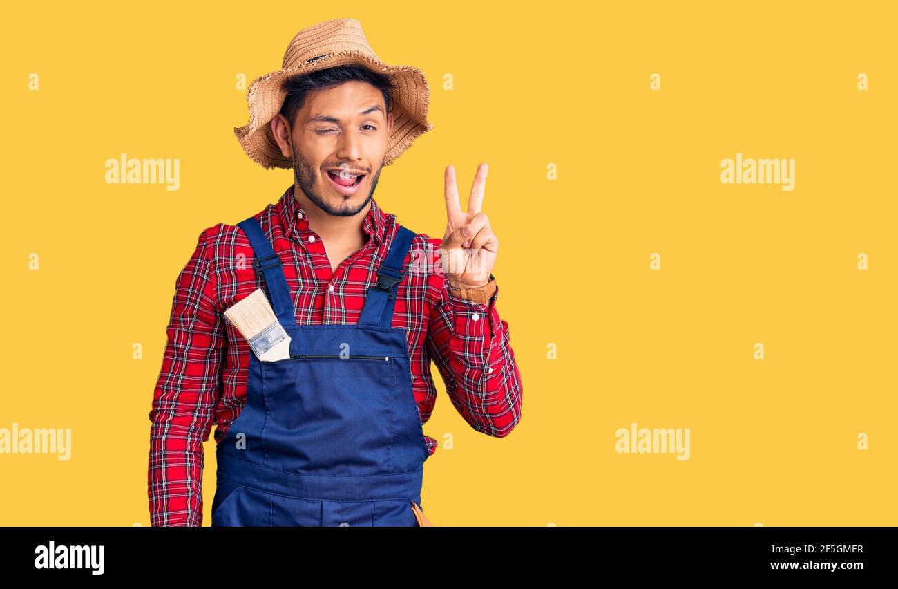 Handsome latin american young man weaing handyman uniform smiling with ...