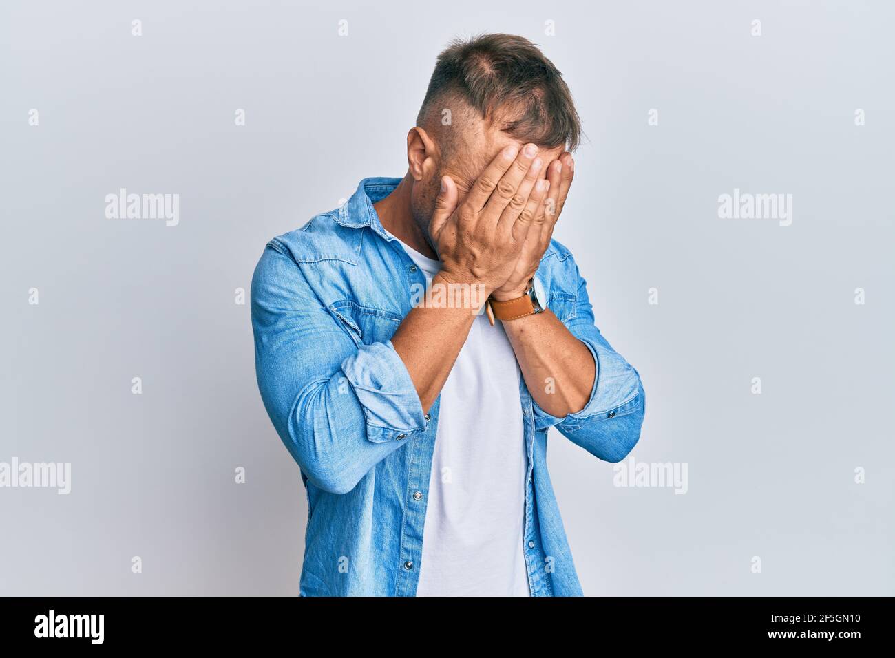Handsome muscle man wearing casual denim jacket with sad expression ...