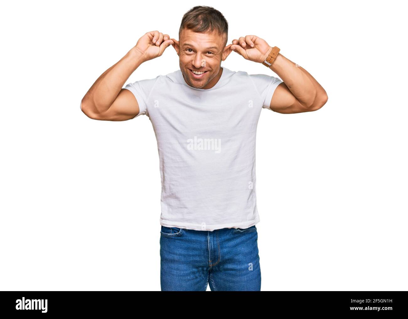 Handsome muscle man wearing casual white tshirt smiling pulling ears ...