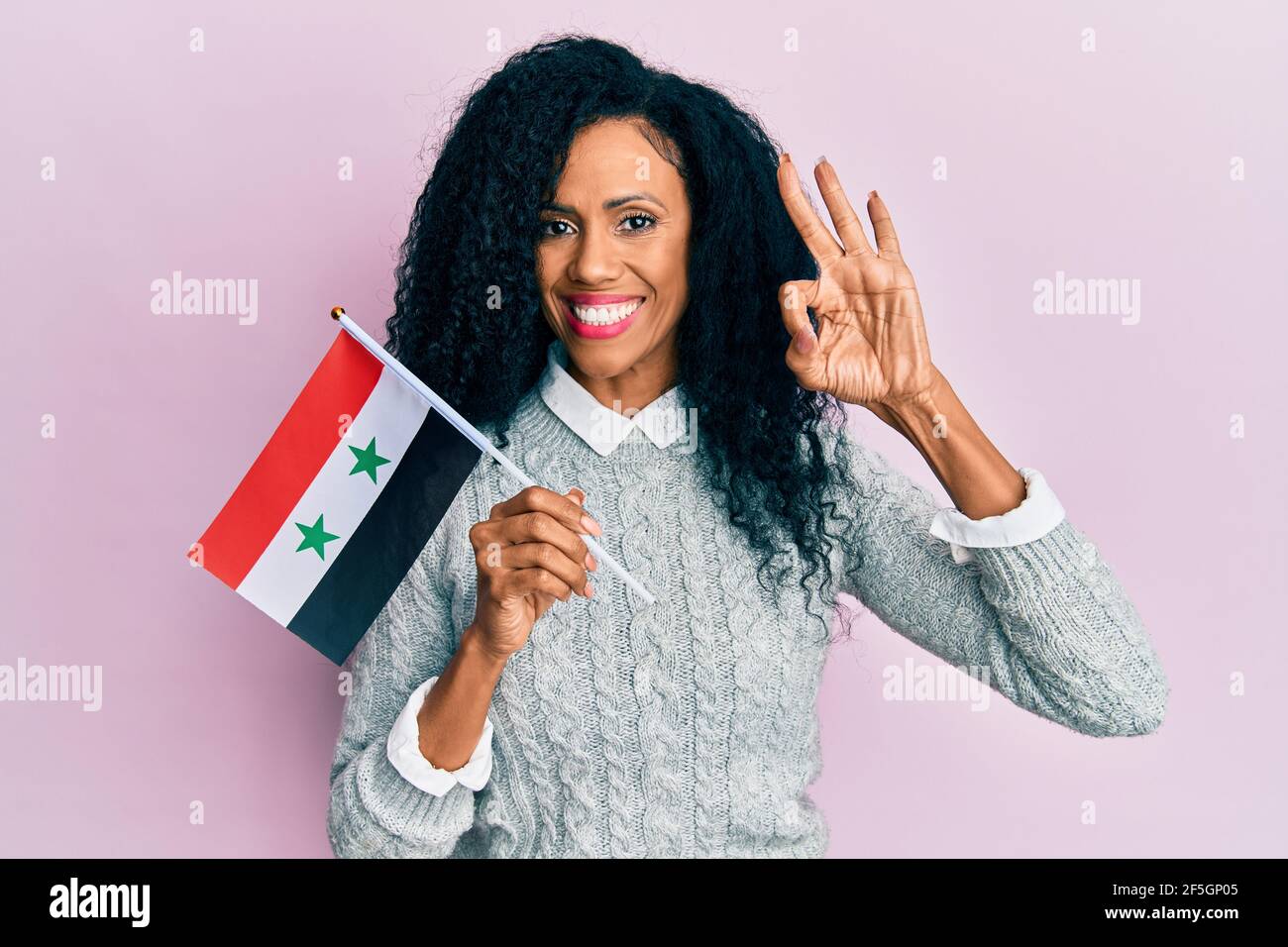 Middle age african american woman holding syria flag doing ok sign with ...