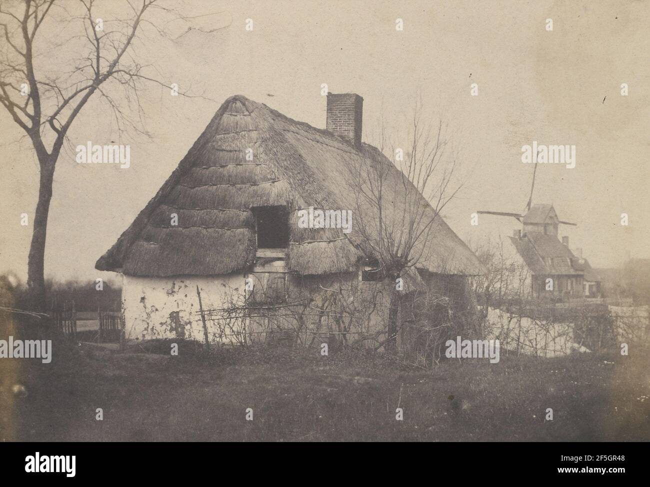 Thatched-roof Building with Windmill Stock Photo - Alamy