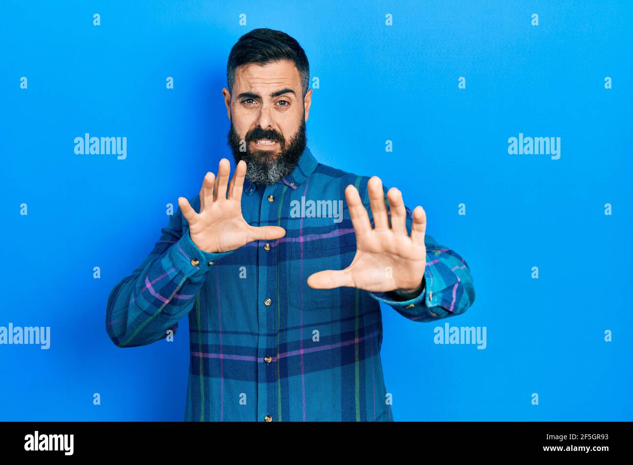Young hispanic man wearing casual clothes afraid and terrified with ...