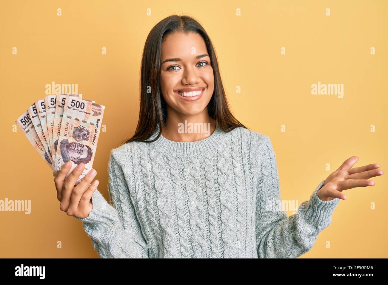 Beautiful hispanic woman holding 500 mexican pesos banknotes ...