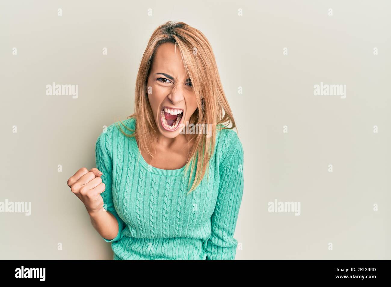 Beautiful blonde woman wearing casual winter sweater angry and mad ...