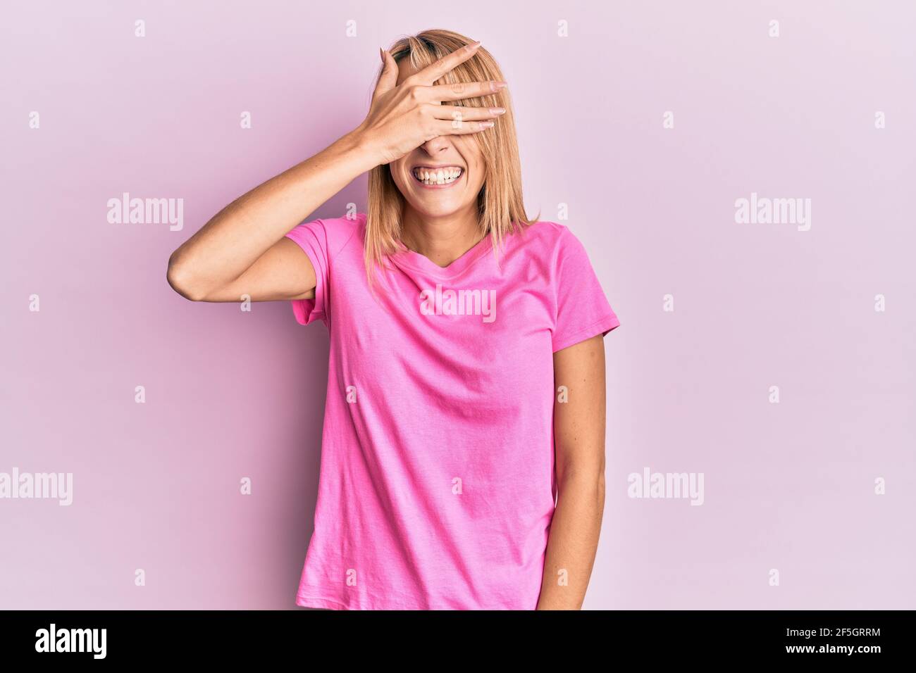 Beautiful blonde woman wearing casual pink tshirt smiling and laughing ...