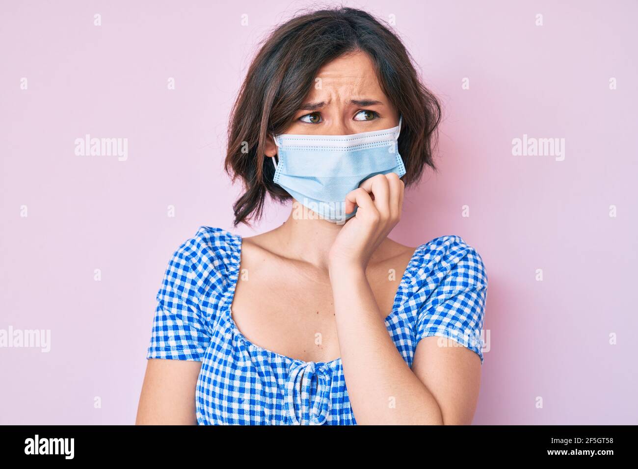 Young beautiful woman wearing medical mask looking stressed and nervous ...