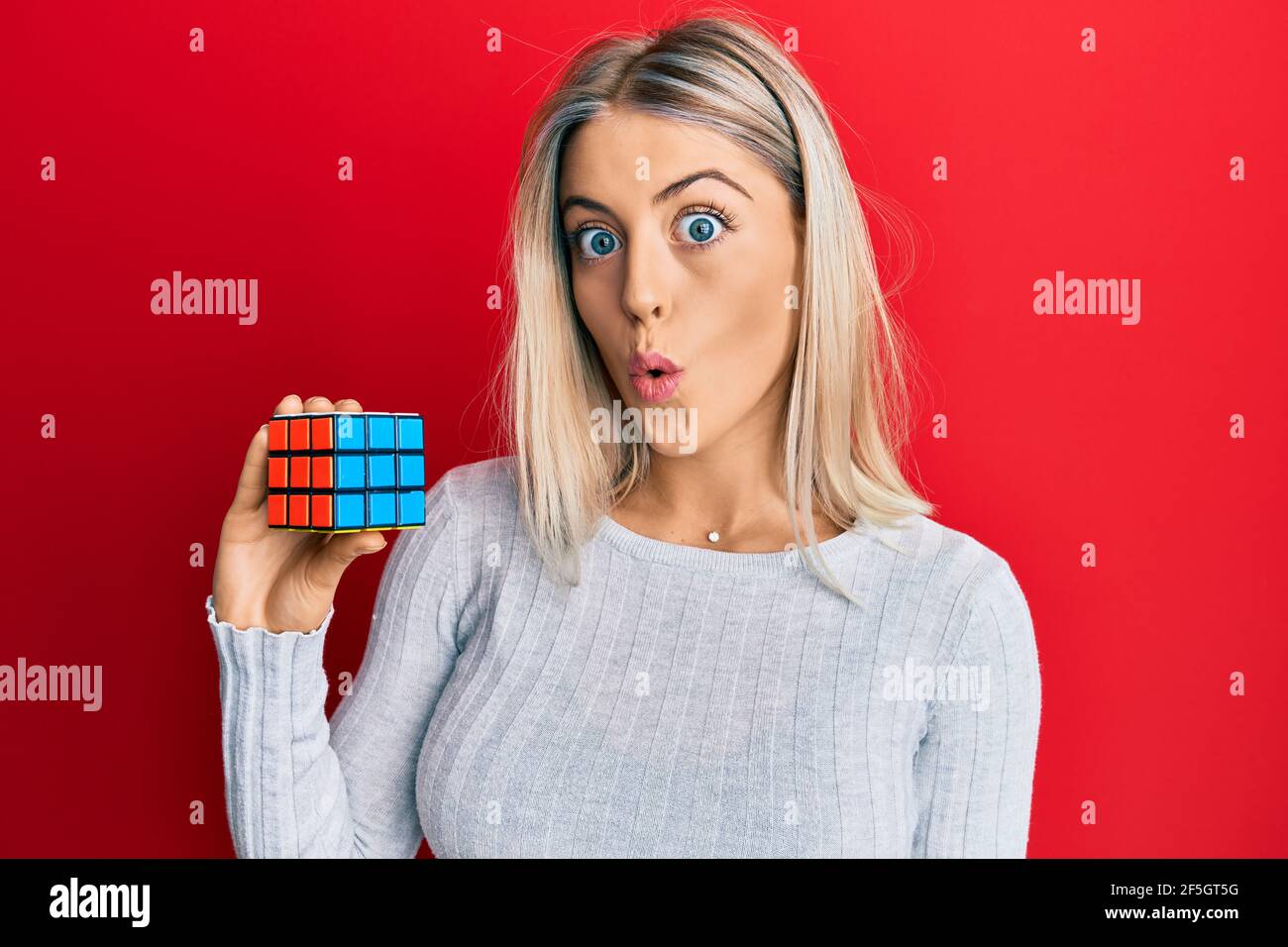 Beautiful blonde woman playing colorful puzzle cube intelligence game ...