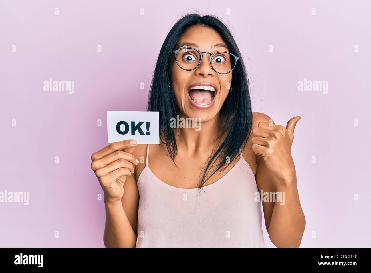 Young african american woman holding ok message paper pointing thumb up ...