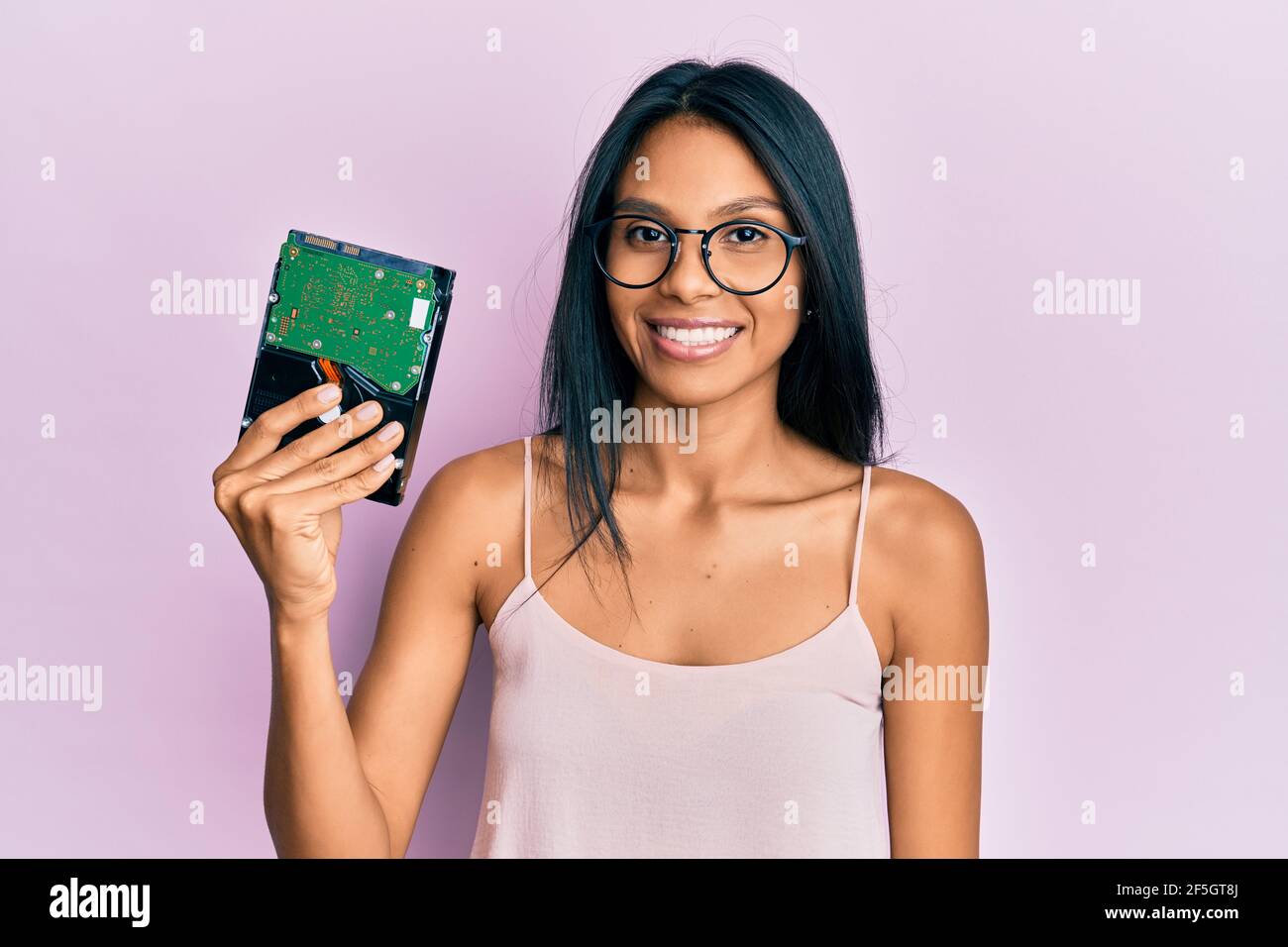 Young african american woman holding hard disk looking positive and ...