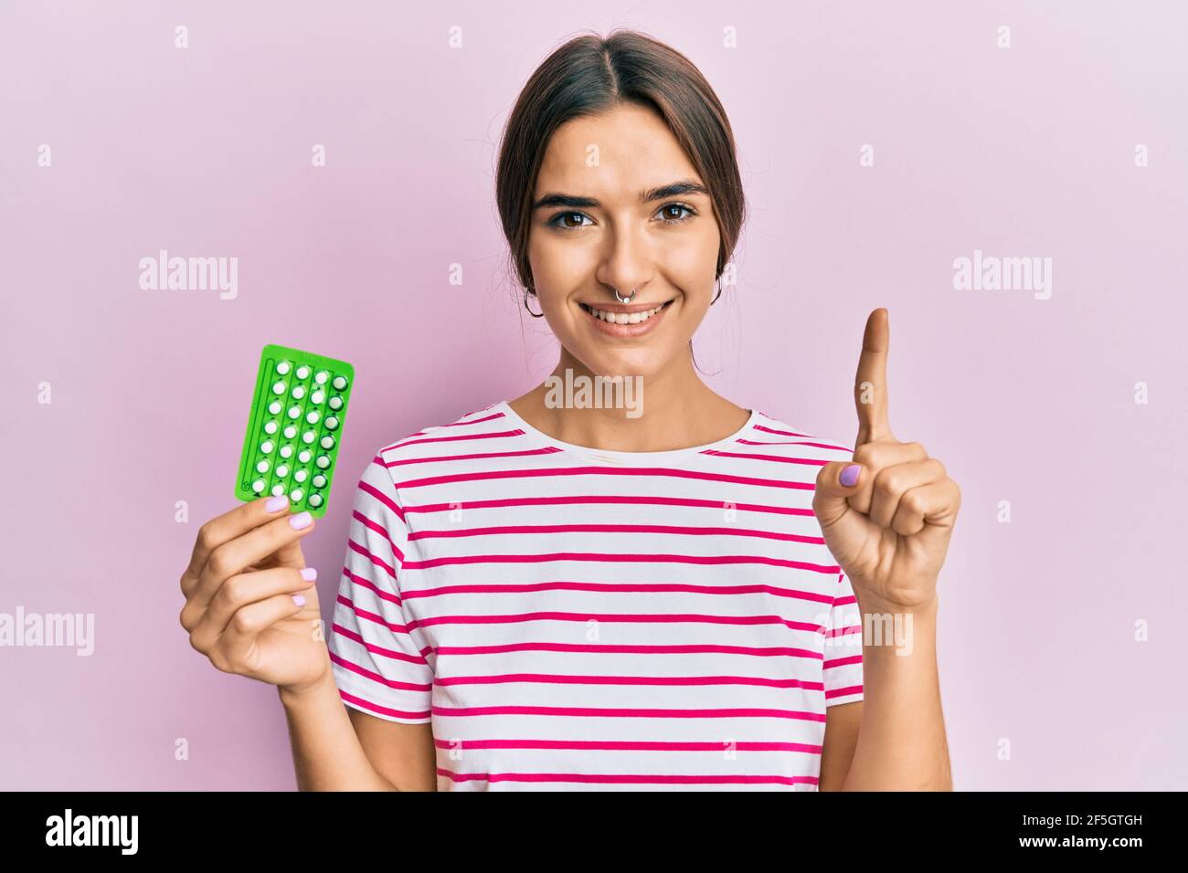 Young hispanic woman holding birth control pills smiling with an idea ...