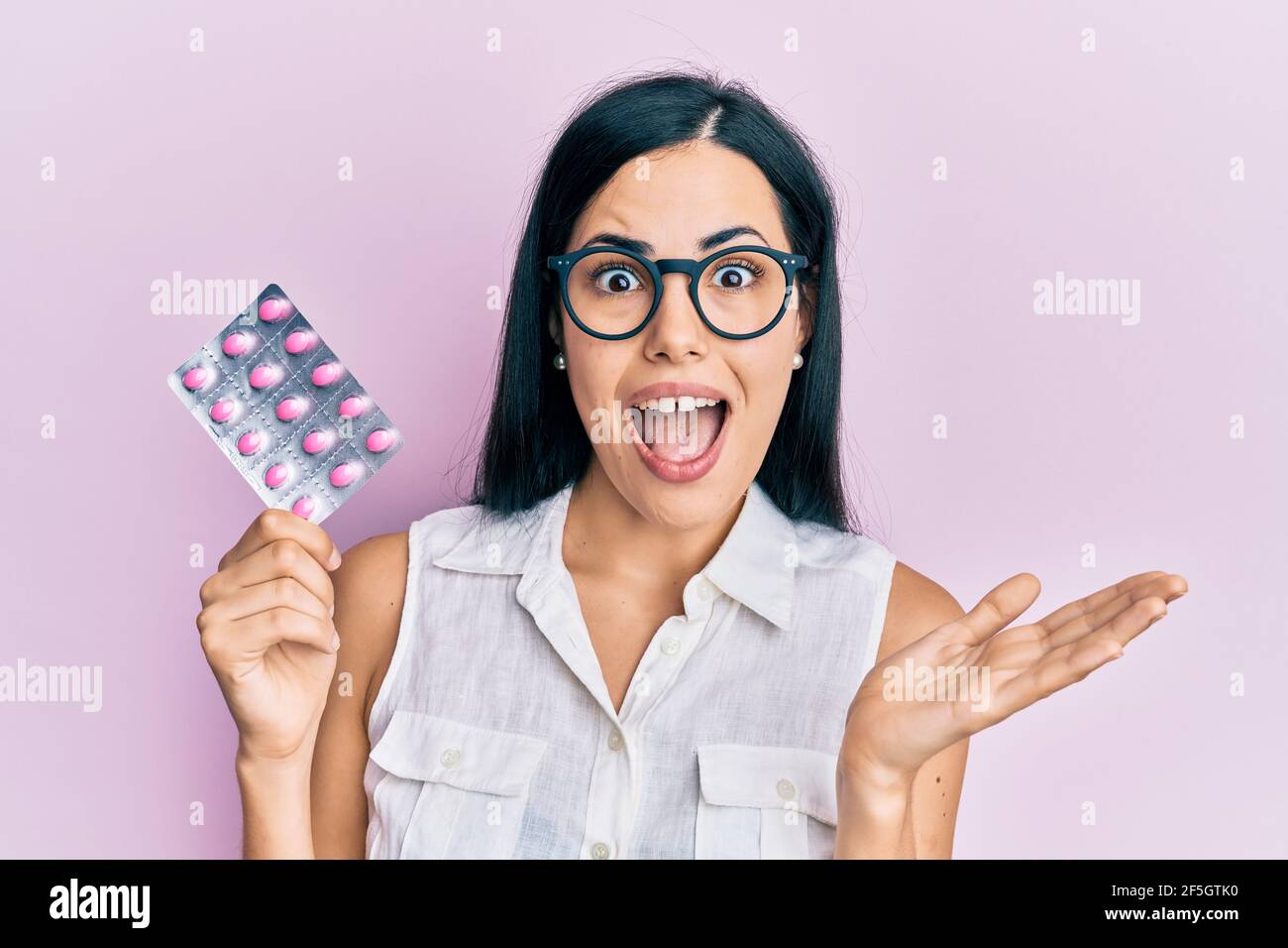 Beautiful young woman holding pills celebrating achievement with happy ...