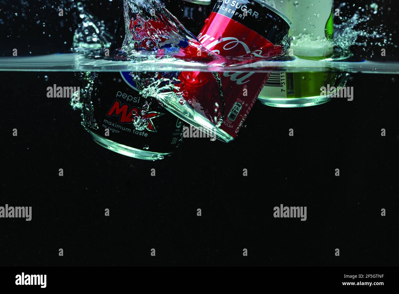 Close up view of two cans falling in water. Coca cola vs Pepsi cola ...