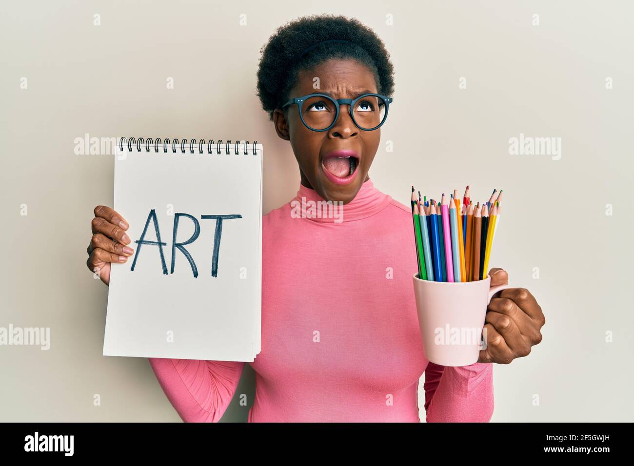 Young african american girl holding art notebook and colored pencils ...