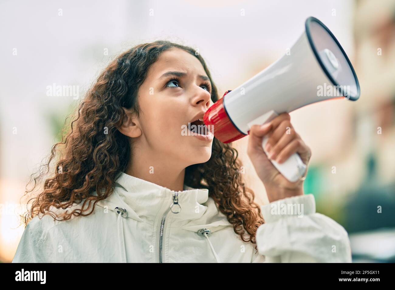 Hispanic child girl shouting angry using megaphone at the city Stock ...