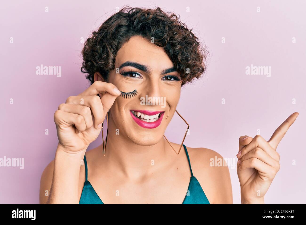 Young man wearing woman make up holding fake lashes smiling happy ...