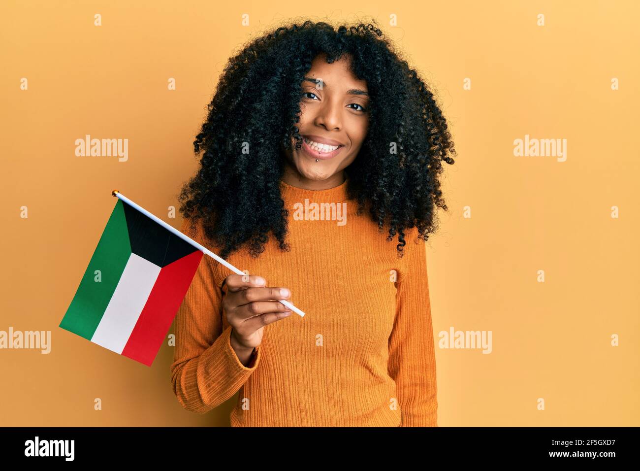 African american woman with afro hair holding kuwait flag looking ...
