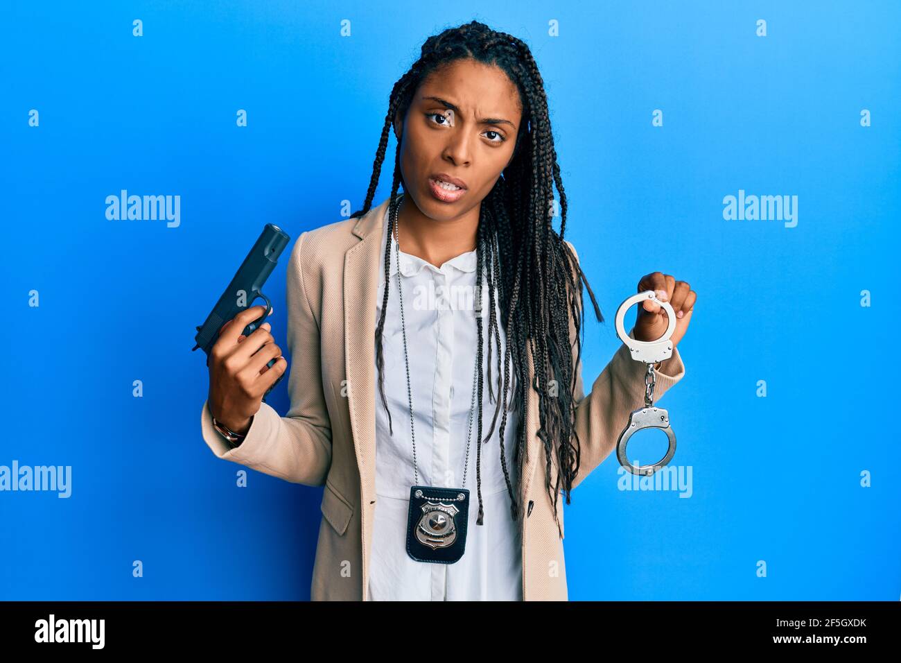 African american police woman holding gun and handcuffs in shock face ...
