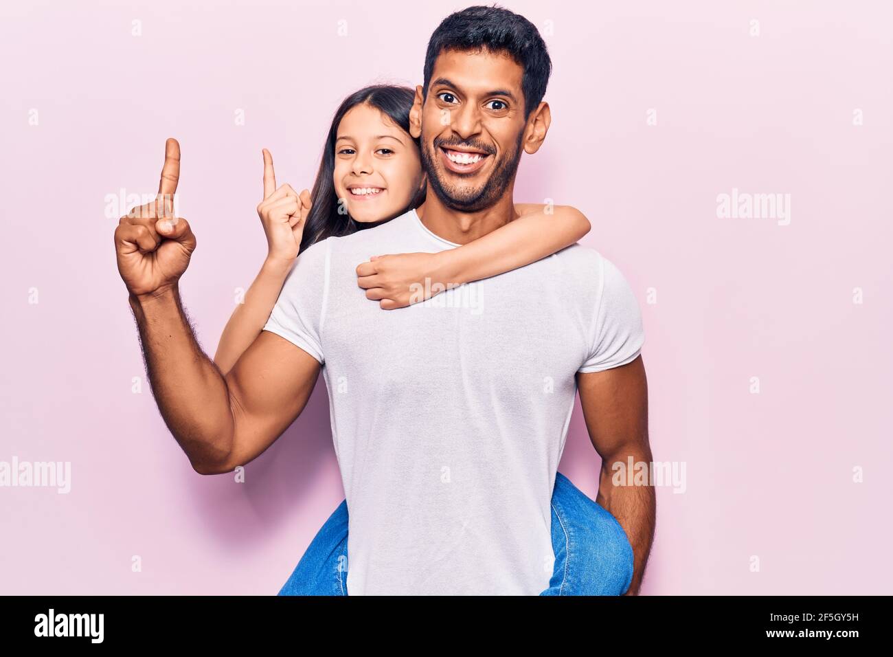 Latin father and daughter wearing casual clothes smiling with an idea ...