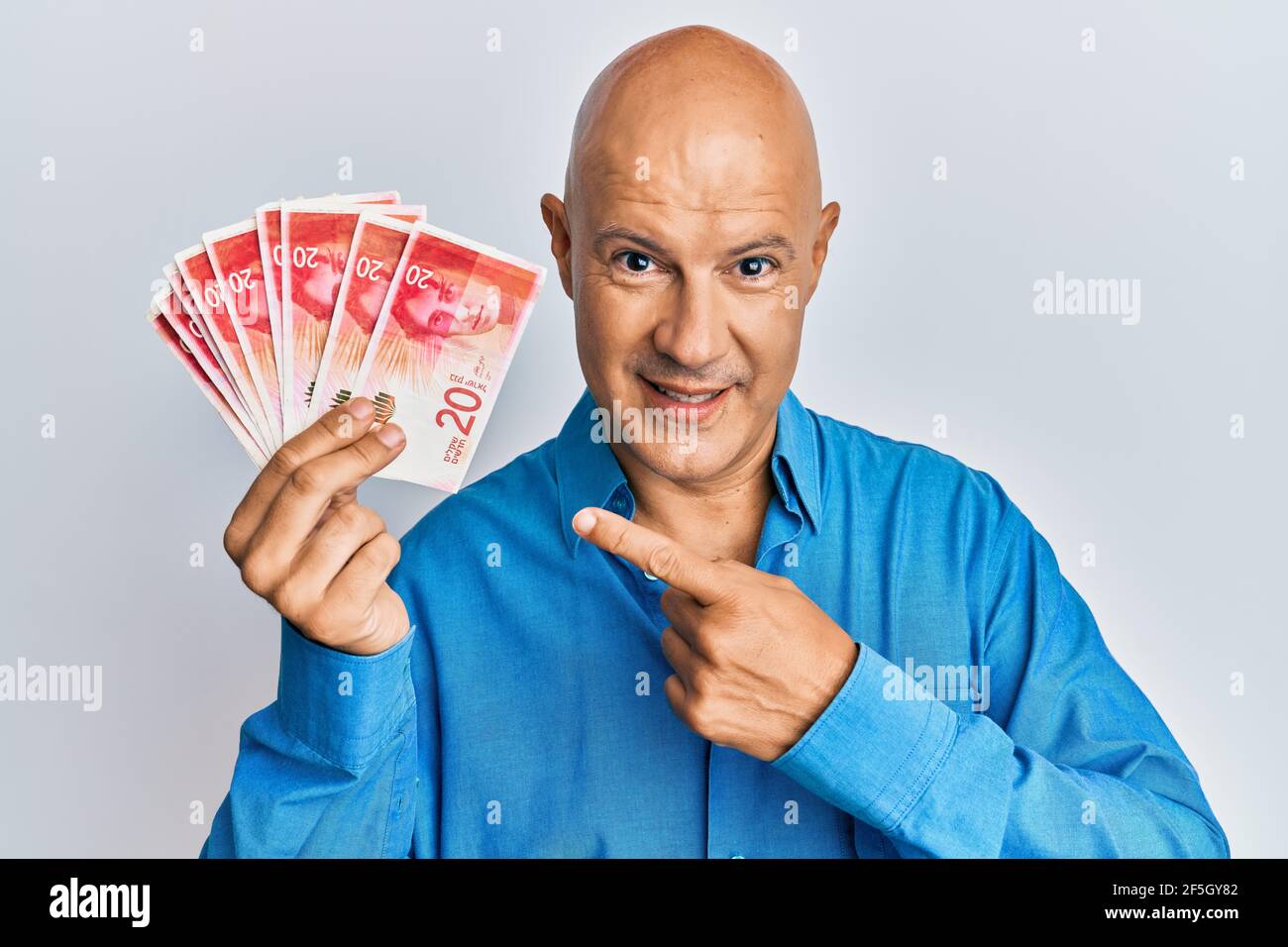 Middle age bald man holding 20 israel shekels banknotes smiling happy ...